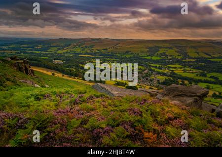 View of Bamford village and flowering purple heather on Bamford Edge ...
