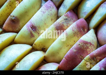 ripe raw cut potatoes wedges spiced on baking tray background closeup ...