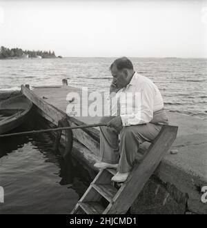 Fishing in the 1940s. A man with a fishing rod has caught a small fish ...