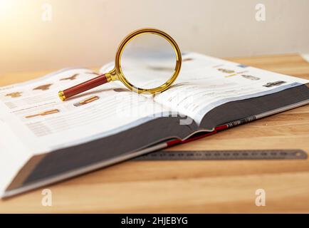 Open technical book for study with magnifying lens and ruler on wooden ...
