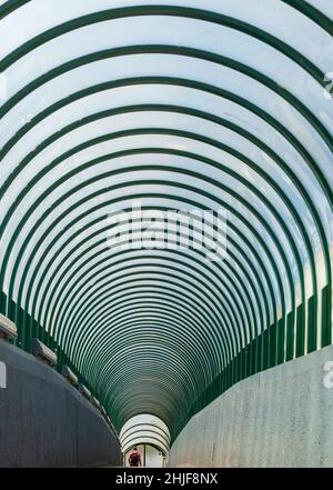 The curved metal hoops of a footbridge over the railway tracks in ...