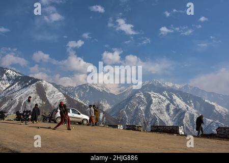 Kashmiri men play cricket on top of the hill with snow covered ...
