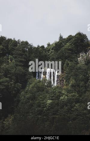 A low angle shot of a waterfall surrounded by trees Stock Photo - Alamy