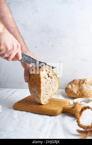 Male hands cutting homemade bread, closeup Stock Photo - Alamy
