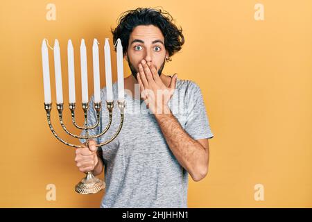 Hispanic man with beard holding menorah hanukkah jewish candle smiling ...