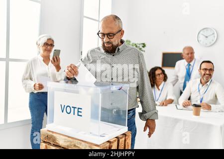 Middle age voter man smiling happy putting vote in voting box at ...
