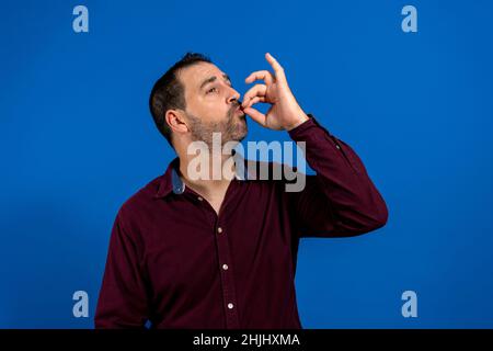 Happy man licking fingers isolated on trendy gray studio background ...