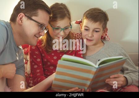 Bonding before bedtime. A father reading a bedtime story to his kids ...