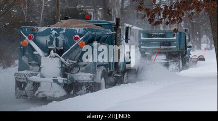 Rear view of municipal snowplow truck spreading grit while clearing ...
