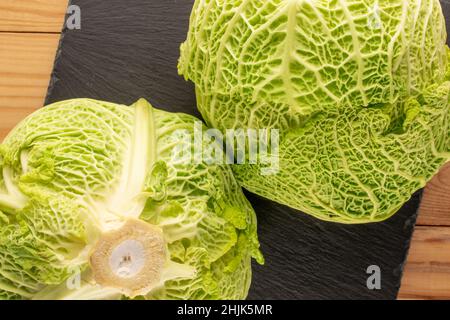 Two bunches of juicy Savoy cabbage on a slate stone, macro, top view ...
