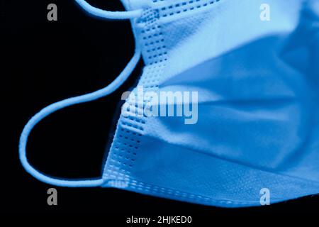 Surgical mask in deep ultramarine tones on dark background - macro ...