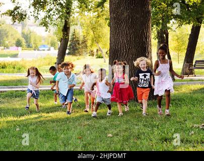 a group of preschoolers running on the grass against the background of ...
