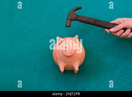 Hand Holding a Hammer Breaking pig coin isolated on green background ...