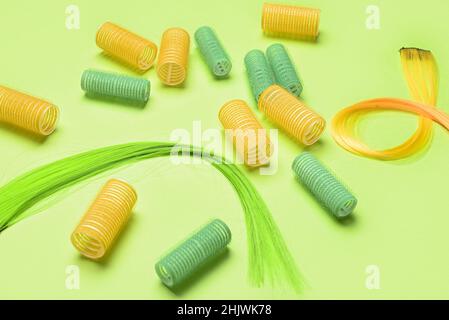 Different hair curlers on green background Stock Photo - Alamy