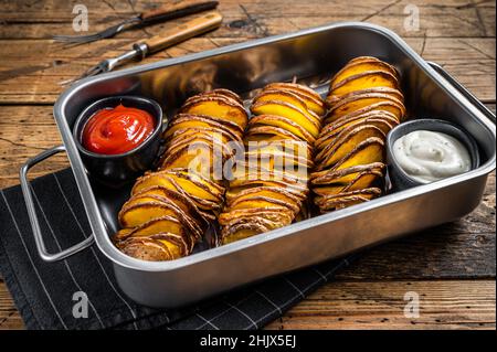 Skewered fried tornado or twist potatoes with ketchup sauce. Wooden ...