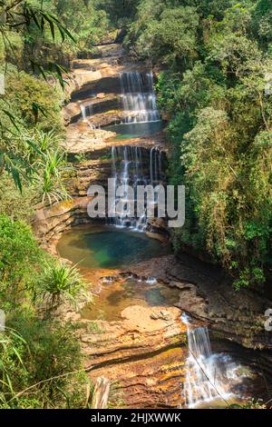 natural waterfall layered falling from mountain top in deep green ...