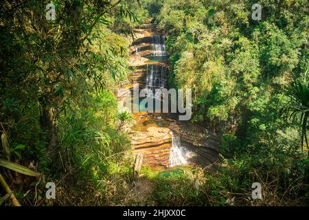 natural waterfall layered falling from mountain top in deep green ...