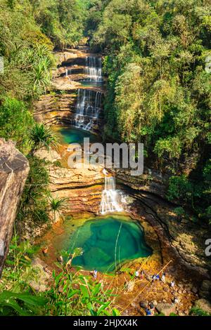 three layered waterfall falling from mountain top in deep green forests ...