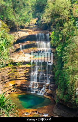 two layered waterfall falling from mountain top in deep green forests ...