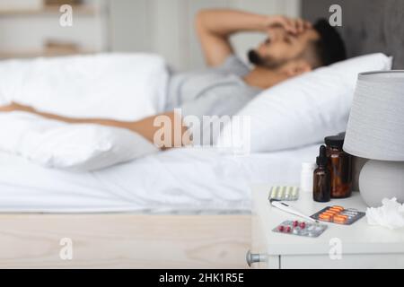 Sick Young Arab Man Lying In Bed With Medicine On Bedside Table, Ill ...