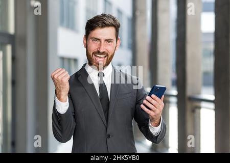 Exited Businessman Celebrating Achievement looking at Smartphone ...