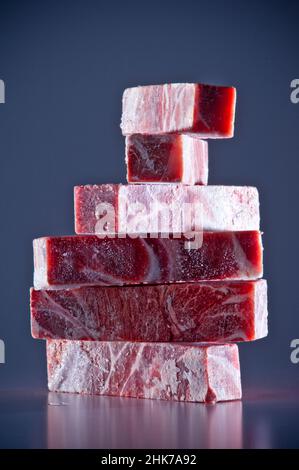 Rectangular cuts of frozen beef stacked on dark background Stock Photo ...