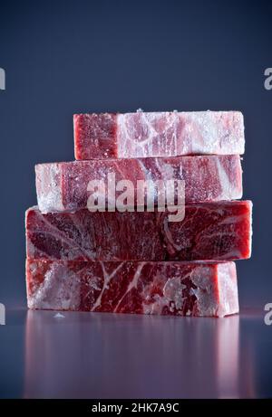 Rectangular cuts of frozen beef stacked on dark background Stock Photo ...