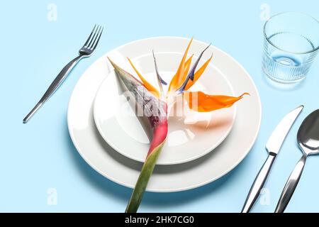 Simple table setting with bird of paradise flower on yellow background ...