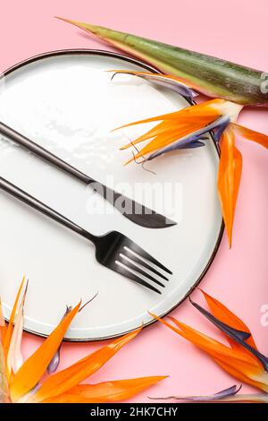 Simple table setting with bird of paradise flower on orange background ...