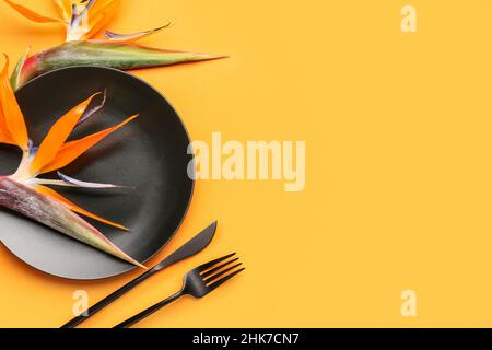 Simple table setting with bird of paradise flower on orange background ...