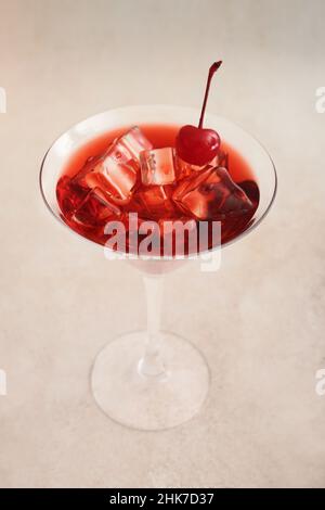Glass of iced Manhattan cocktail with cherry on light background ...