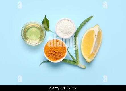 Bowls with turmeric mask, powder, lemon and oil on blue background ...