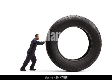 Man pushing a spare car tire towards a SUV isolated on white background ...