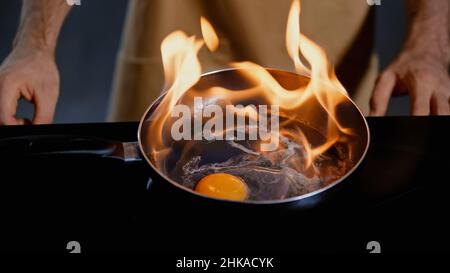 cropped view of man frying chicken egg with flambe method Stock Photo ...