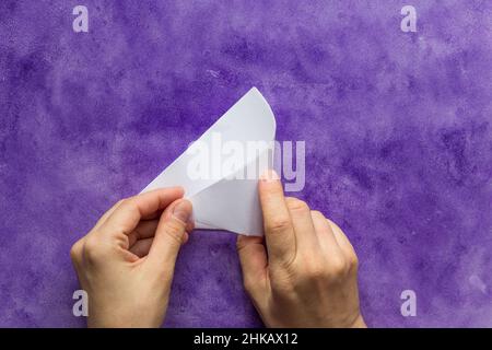 Woman hands folding paper triangle to make smaller one on black ...
