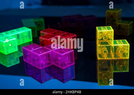 three-dimensional tetris. scattered colored tetris figures on glossy ...