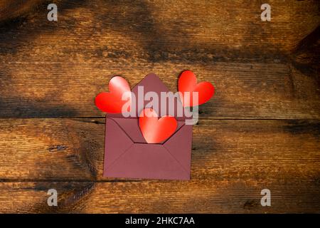 Open envelope with red hearts. Dark wooden background. Love ...