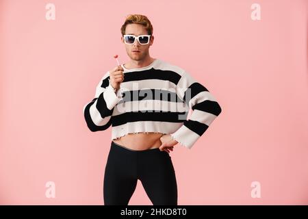 Ginger young man wearing sunglasses smiling while posing with heel ...