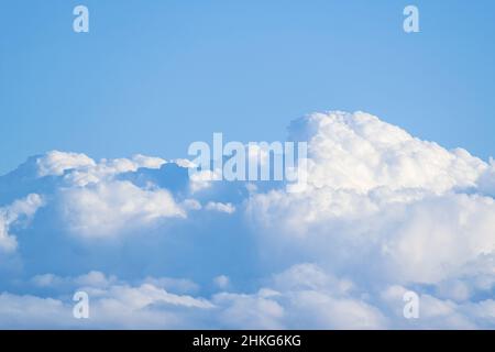 Large fluffy cumulus cloud against vivid blue sky, symbolizing weather ...