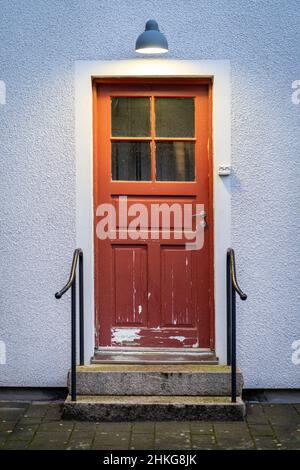 Worn out facade with a wooden gate and a creeper plant hanging from the ...
