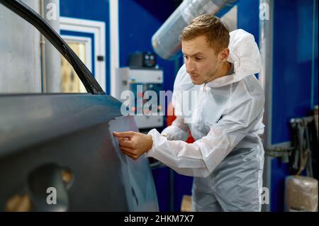 Painter examining car body paint check process Stock Photo - Alamy