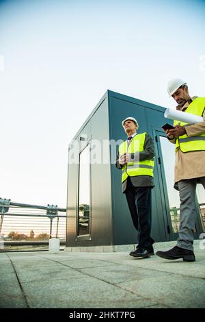 Two senior construction managers are walking and talking about the ...