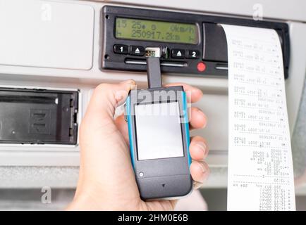Driver holding a digital tachograph reader with big red cross mark on ...