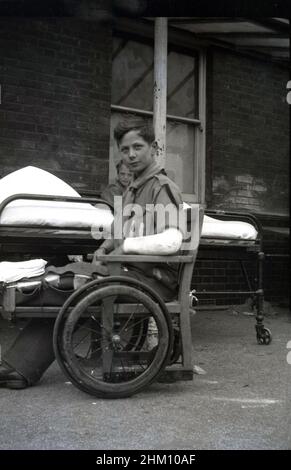 1942, historical, injured boy scout in leg braces, standing outside ...
