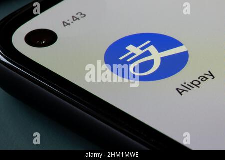 Alipay app icon is seen on a smartphone on top of an iPad screen ...