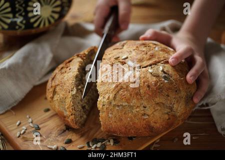 Girl's hand cuts cereal bread Stock Photo - Alamy