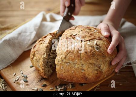 Girl's hand cuts cereal bread Stock Photo - Alamy