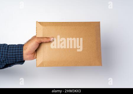 Male hand holding parcel post against white background Stock Photo - Alamy