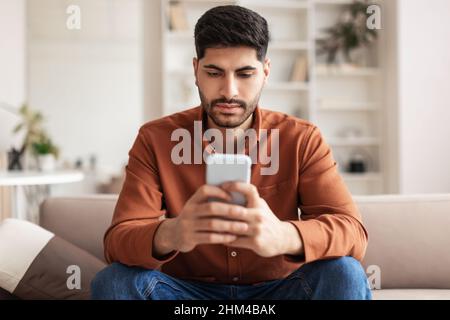 Young arab man using smartphone ironing clothes at laundry room Stock ...