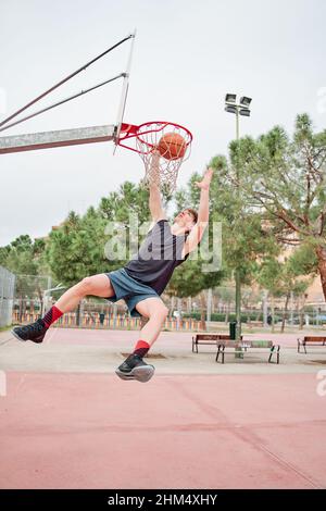 Young Basketball street player making slam dunk Stock Photo - Alamy